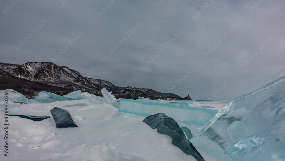 Blocks of ice hummocks on a frozen and snowy lake. Turquoise shiny ice ...