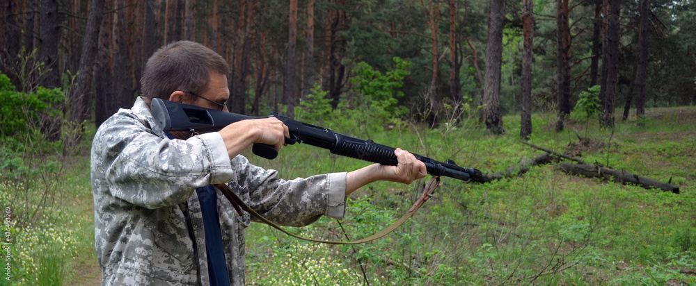 Man with 12-gauge rifle (pump action shotgun). Unformal shooting range ...