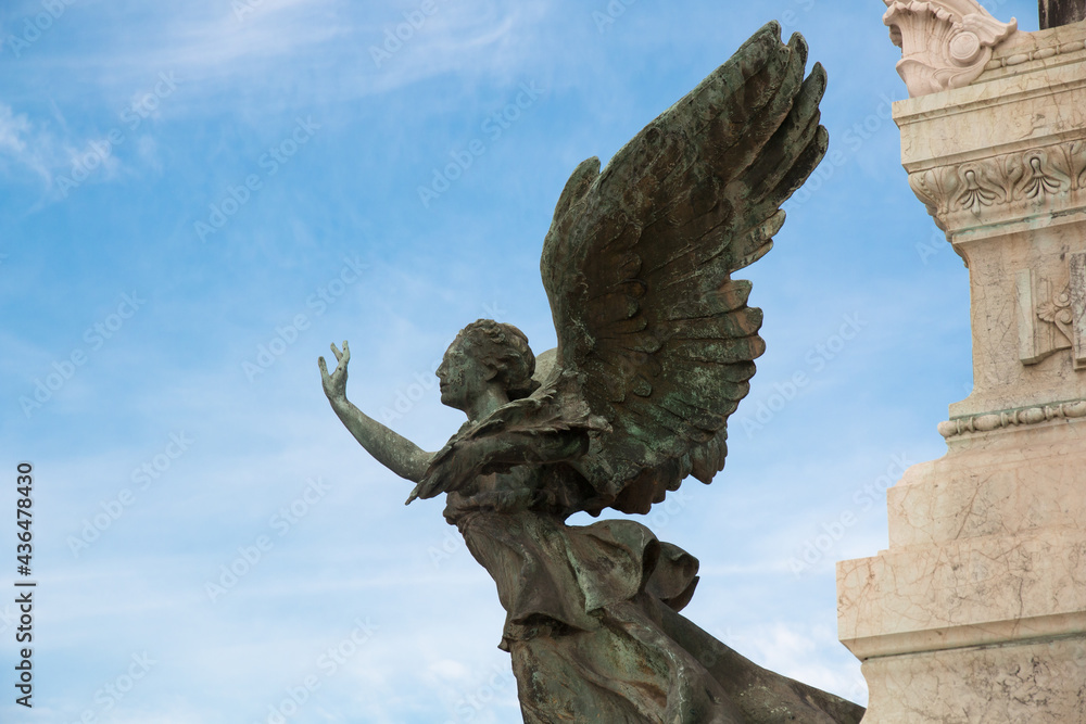 Old statue of an angel reaching for the sky on a blue background in ...