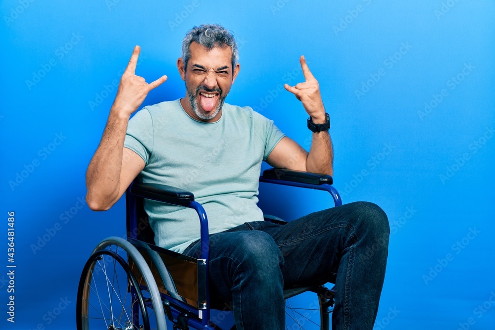 Handsome middle age man with grey hair sitting on wheelchair shouting ...