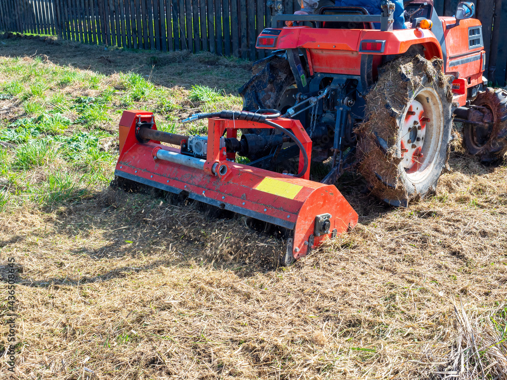 close-up of a tractor with a chain mower chopping dry grass ...