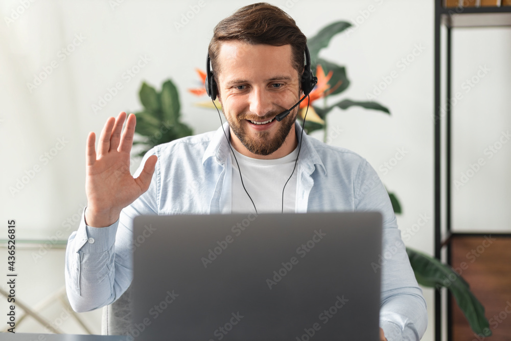 Smiling Indian man in headset with a microphone sit at desk at home ...