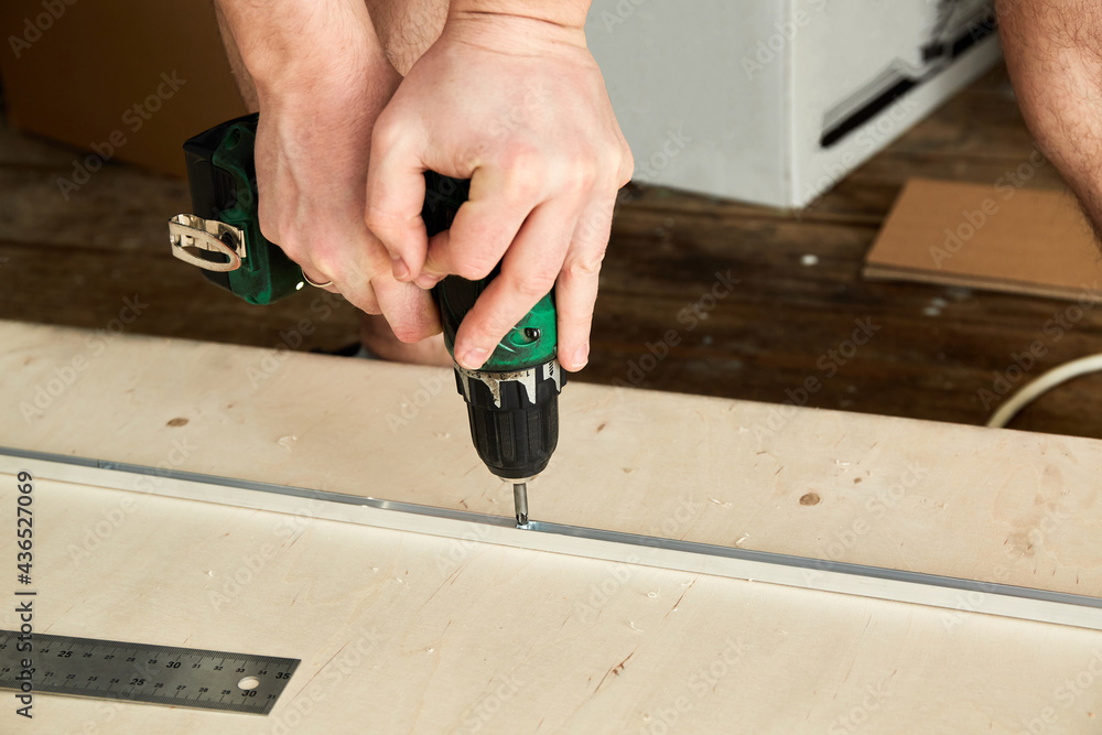 Electric power screwdriver. Carpenter working with hand tool on plywood ...
