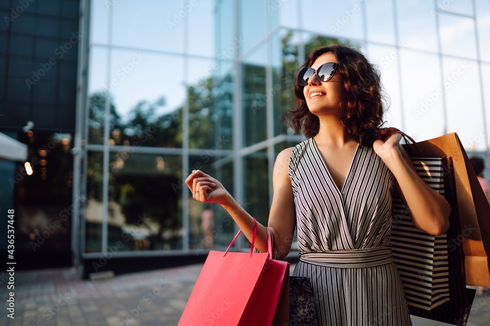 Young woman after shopping with shopping bags walking on street. The ...