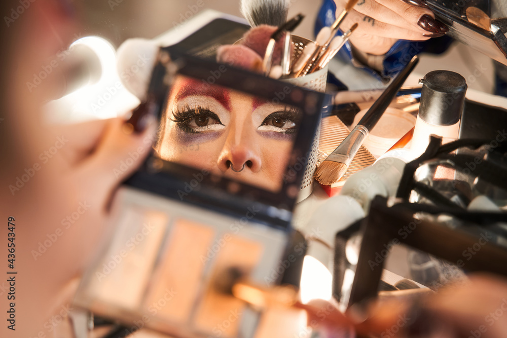 Reflexion at the hand mirror of the face of drag queen making bright ...