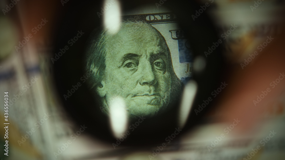 Front side of hundred dollar banknotes examine with magnifying glass ...
