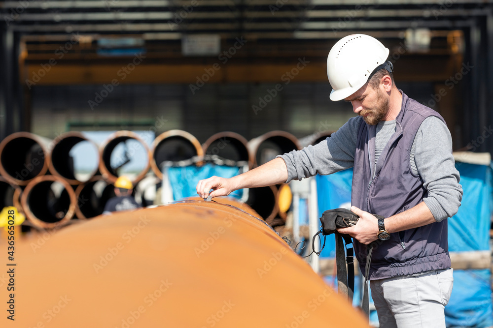 Non-destructive testing technician is checking welds of pipe with ...