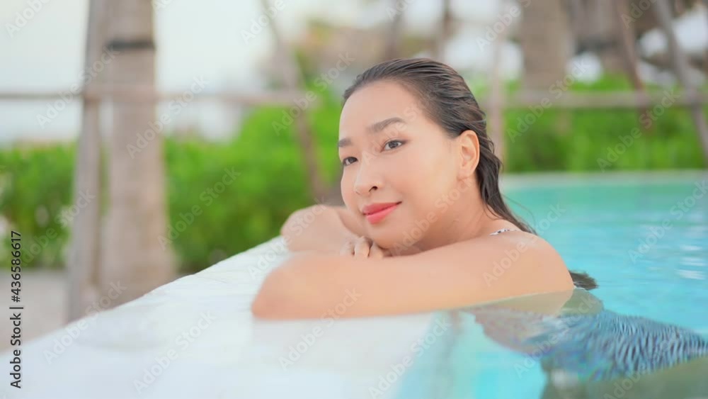 Pretty young lady leaning on the edge of a swimming pool with her face ...