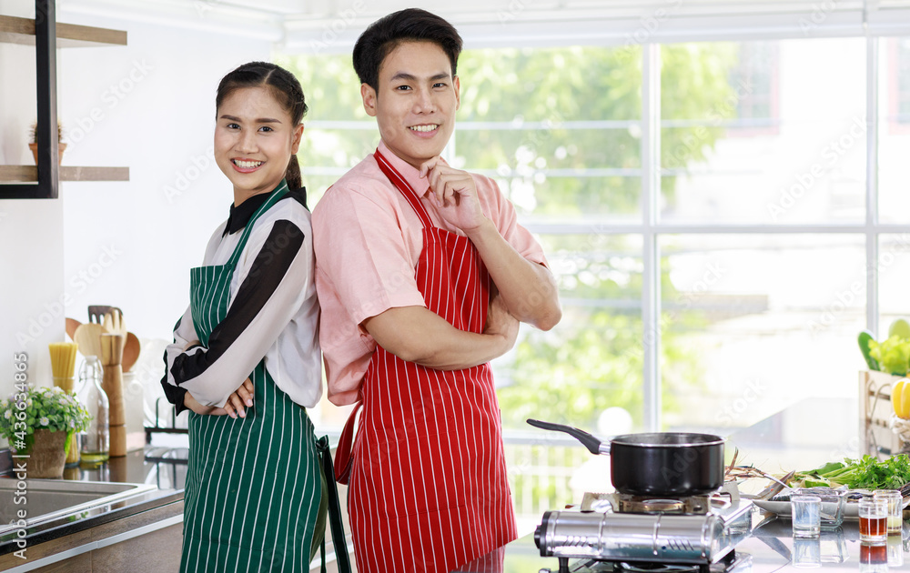 Asian happy husband and skill wife lovers chef couple wear apron stand ...