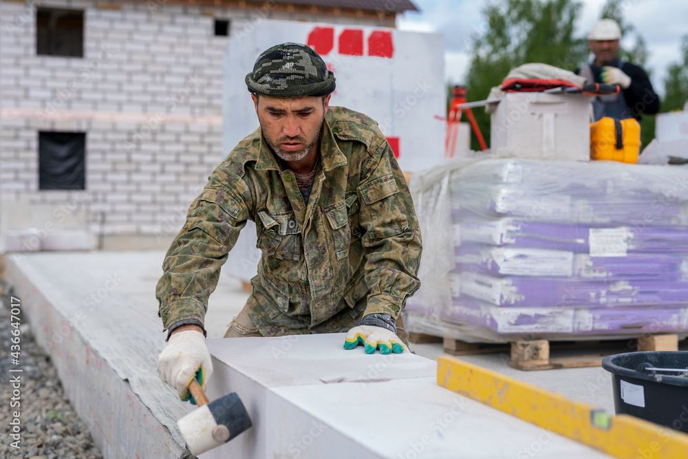 construction of buildings from aerated concrete. The worker levels the ...