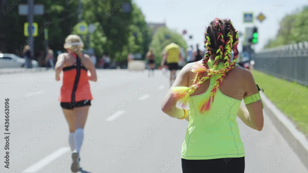 Woman with colorful braids wearing bright sports top and smartphone on ...