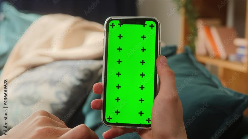 Close-up of smartphone with green screen, young man hands holding ...
