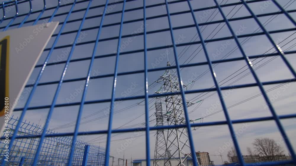Blue grid with High voltage awareness sign near tower with lines at ...