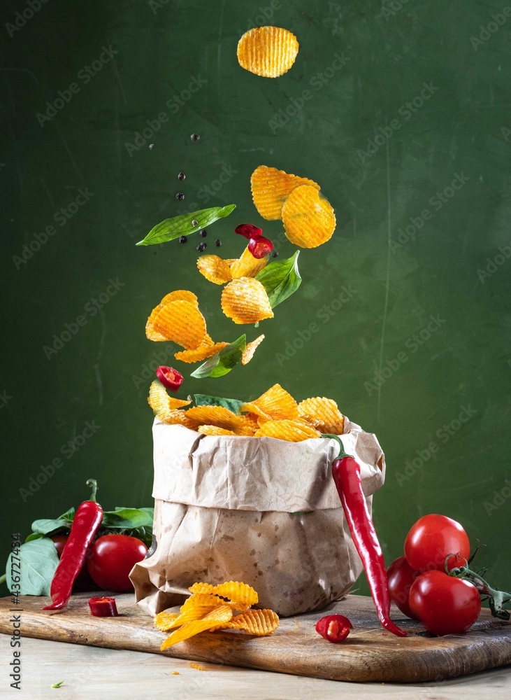 Potato chips fall into a paper bag. Spicy chips in a craft bag. Flying ...