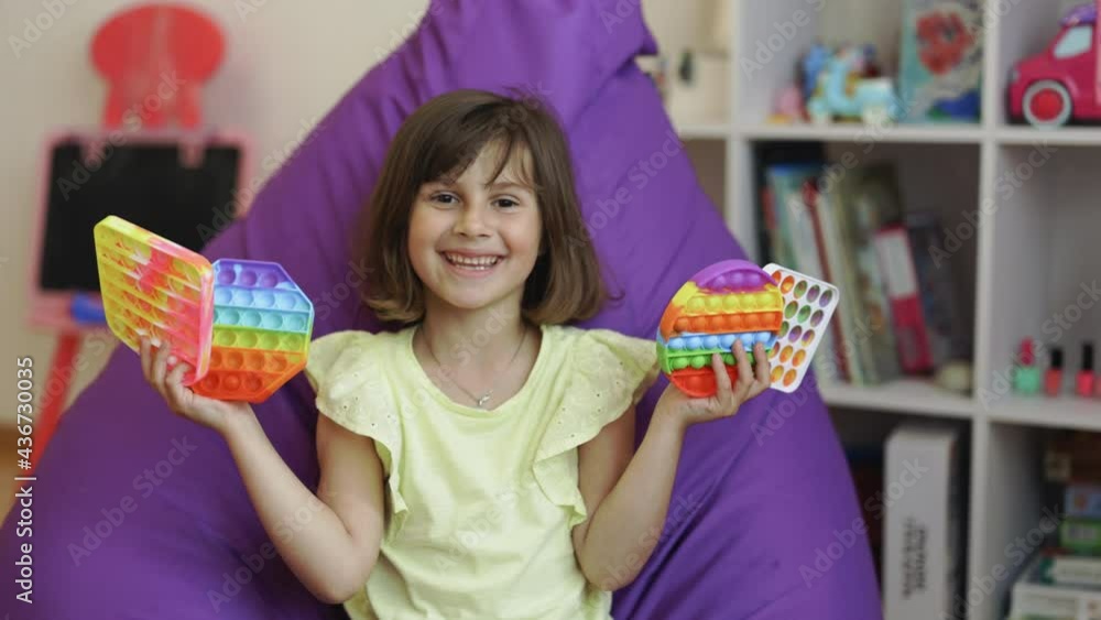 Portrait little girl with a modern popit toy. Colorful and bright pop ...
