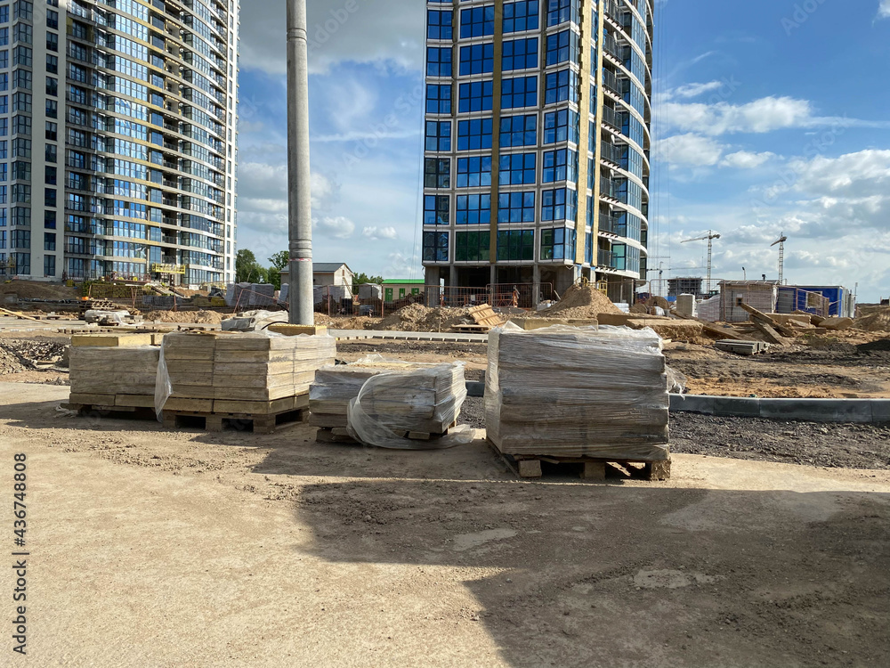 Building materials, paving slabs and curbs lie in front of modern new ...