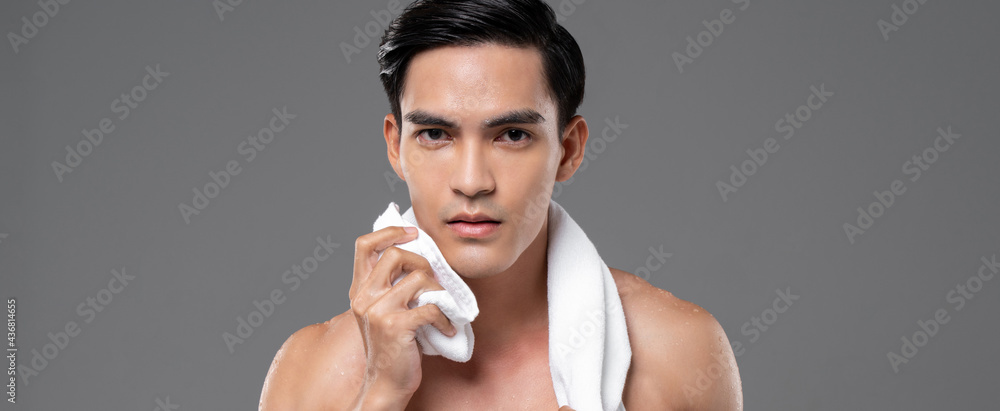 Young handsome shirtless Southeast Asian man wiping his face with towel ...