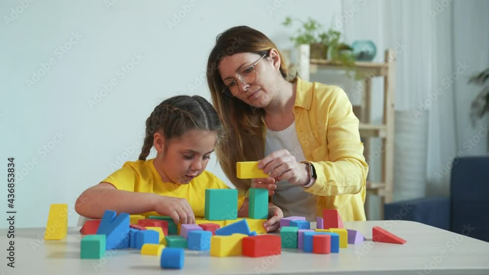 Happy family. Mom and daughter are building house from construction set ...