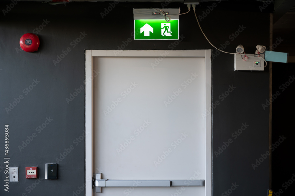 Close-up A fire exit with the sign and red alarm bell above the white ...