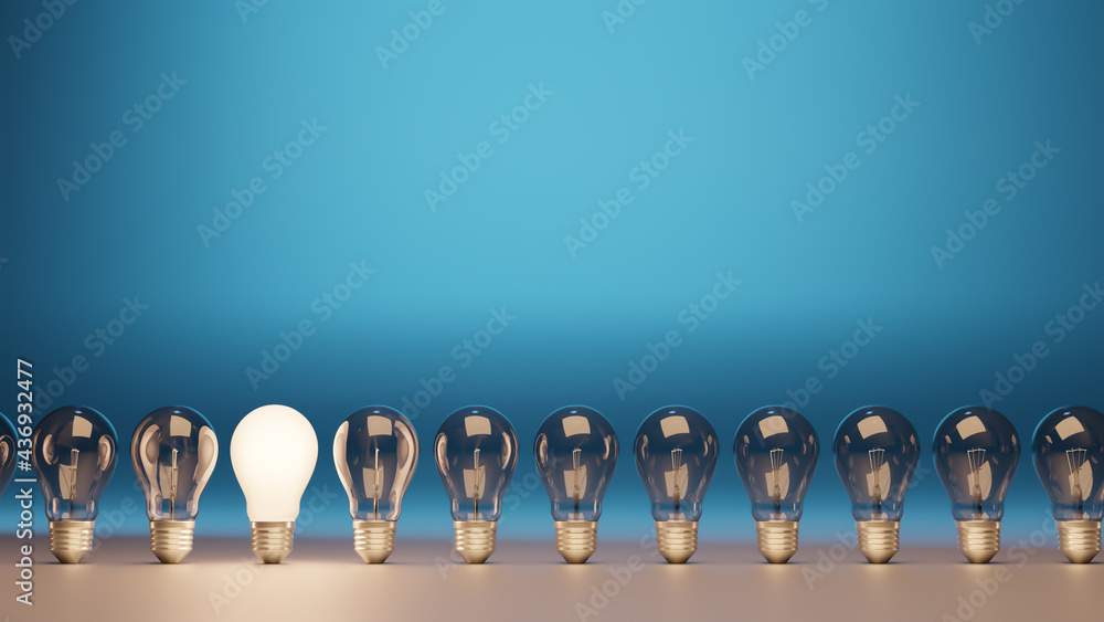 light bulbs in a row on blue background with one illuminated and space ...