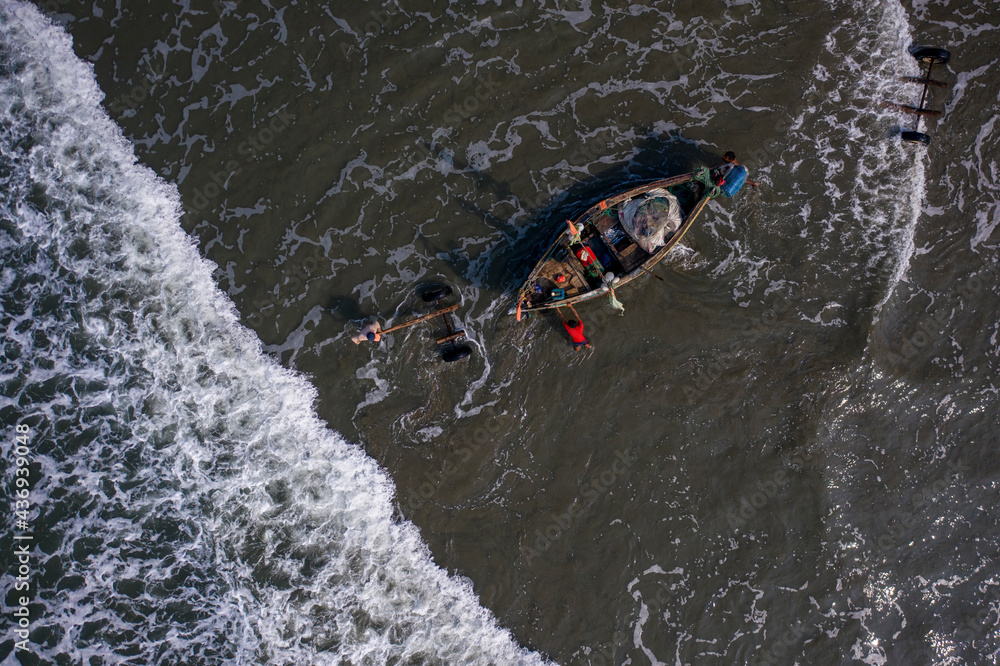 Aerial view of a few people pushing a traditional canoe along the ...