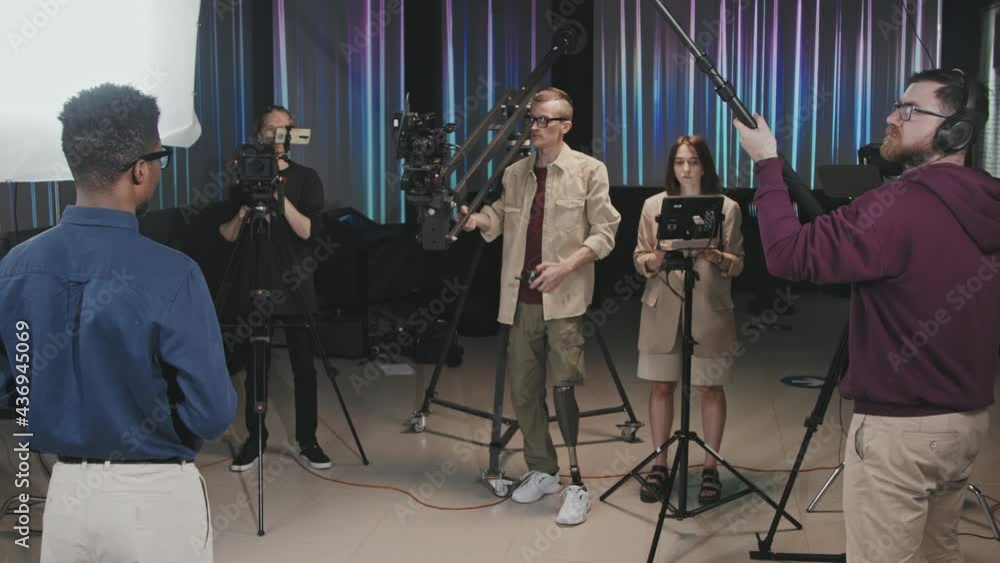 Full shot of professional cameraman with prosthetic leg shooting video ...