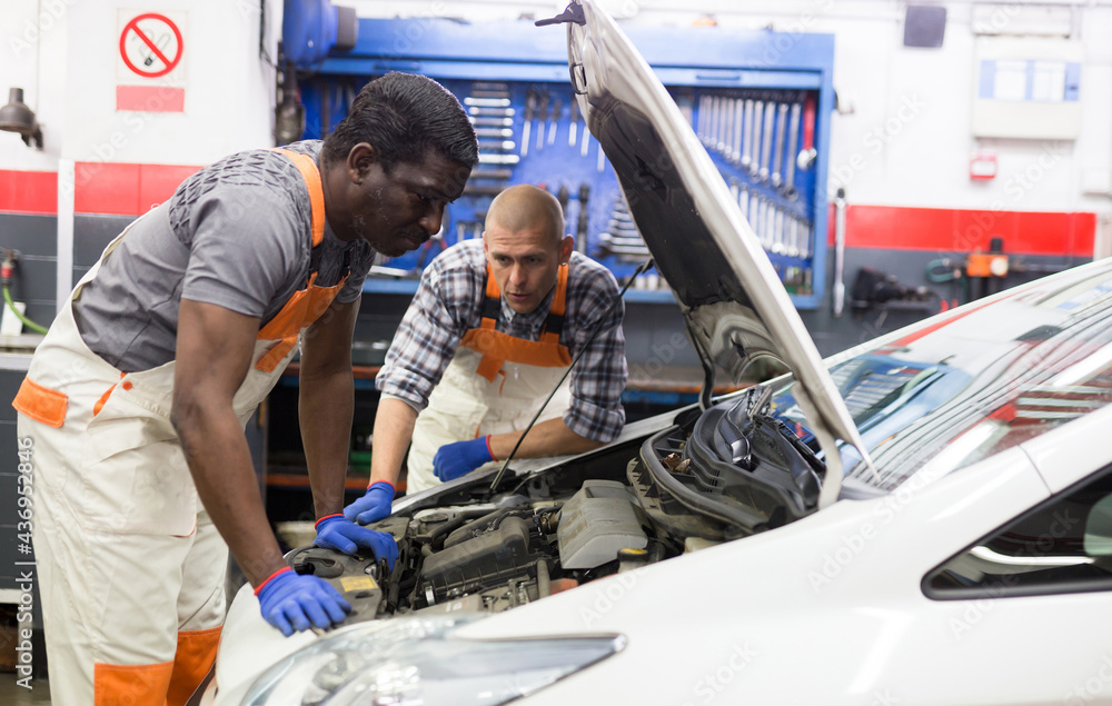 Professional american mechanic man in uniform repairing car engine in ...
