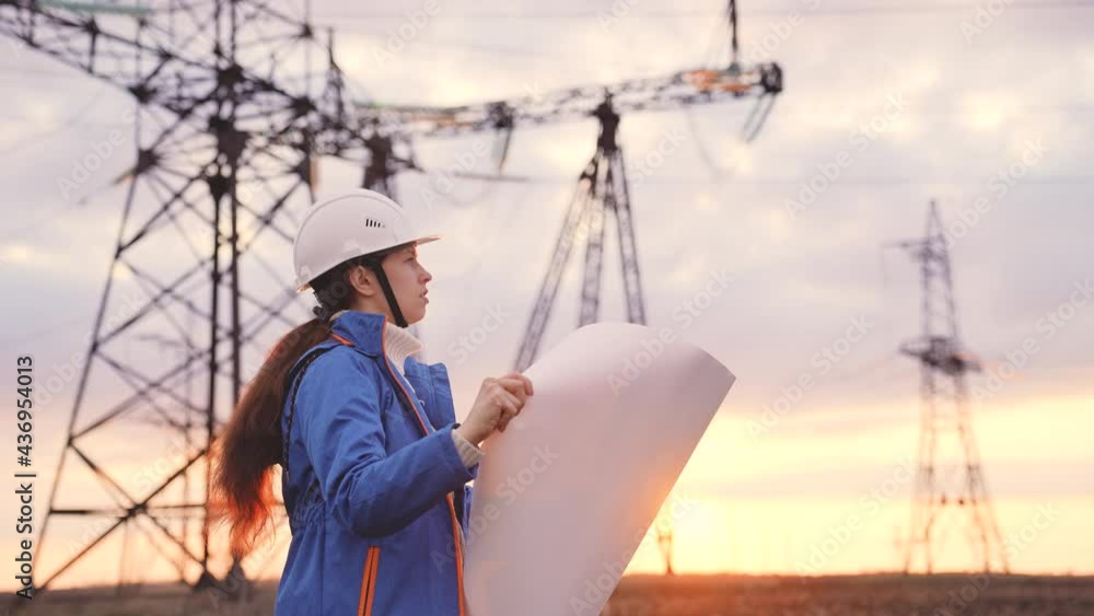 Stockvideon An electrician on the background of high towers of power ...