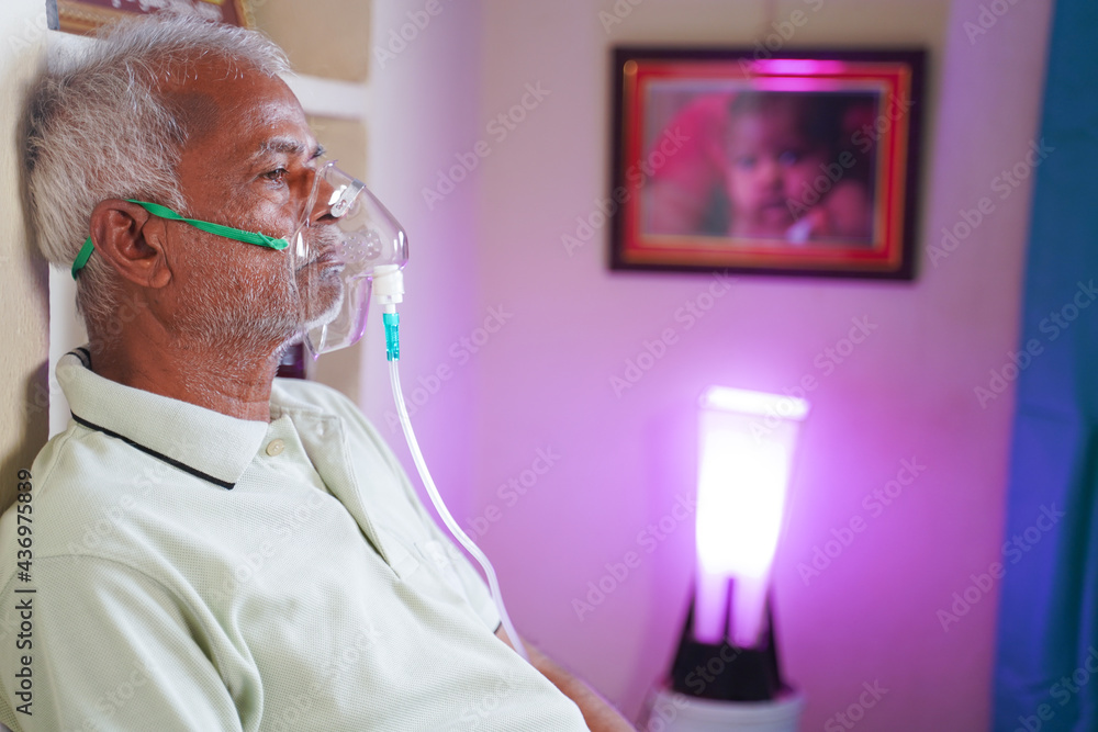 Old man with Oxygen concentrator mask reading news using mobile phone ...