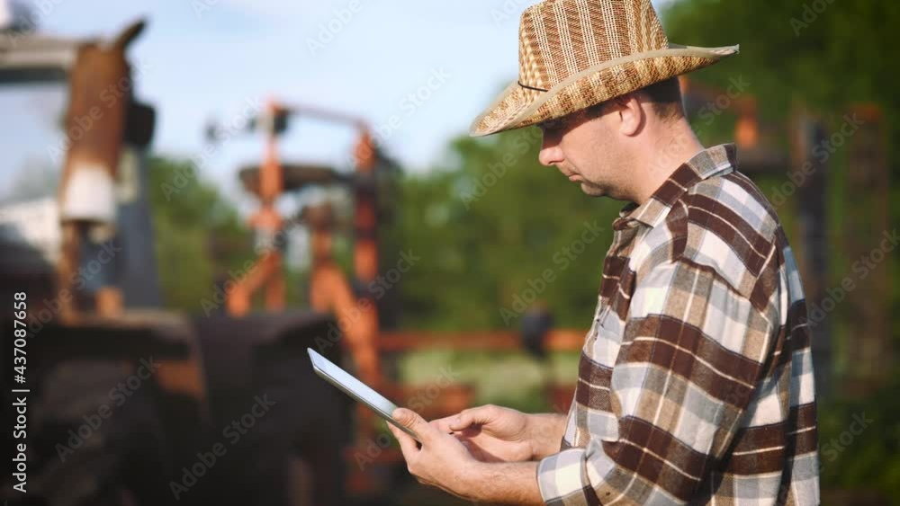 Smart farming. Farmer using digital tablet computer with tractor in the ...