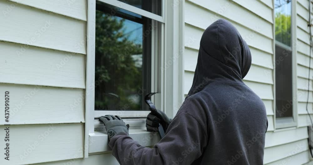 Burglar pries open a window with a crowbar and starts to climb into a ...
