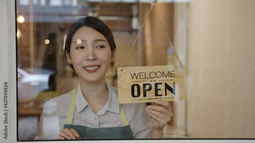 Asian female woman store owner rotating hanged CLOSED or OPEN sign in ...