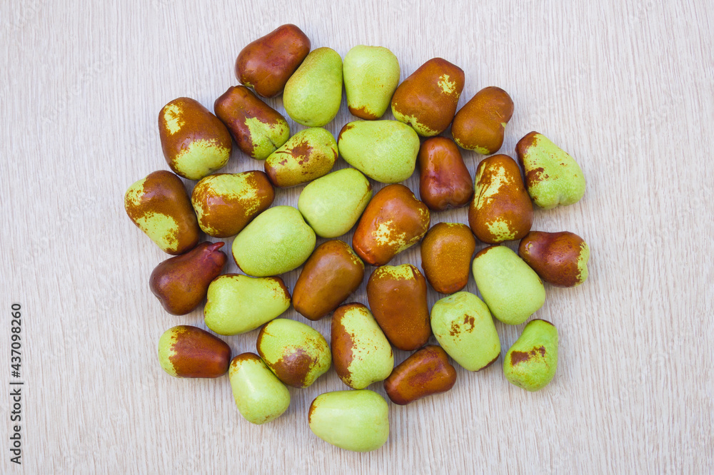 Brown and green dates with water droplets on a light wood background ...