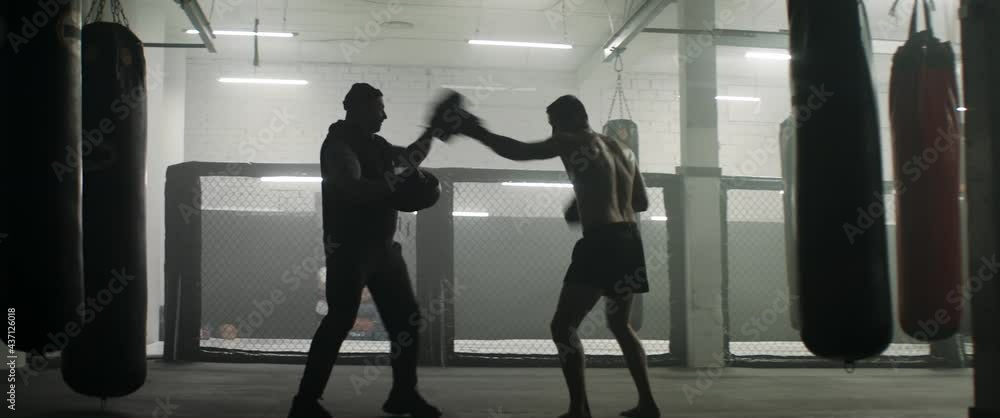 WIDE to CU Caucasian male boxer practicing with his trainer in a boxing ...