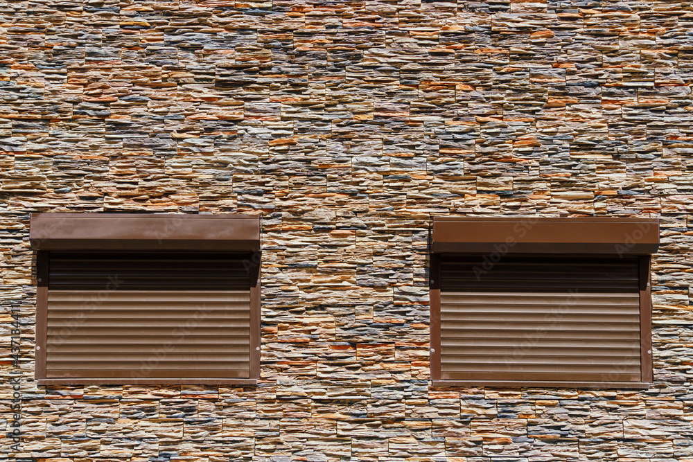 decorative stone wall and window with roller shutters for background or ...