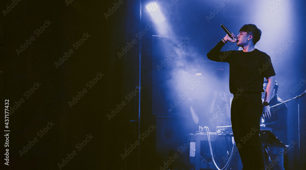 Singer holding a microphone stand and performing on stage. Rock concert ...