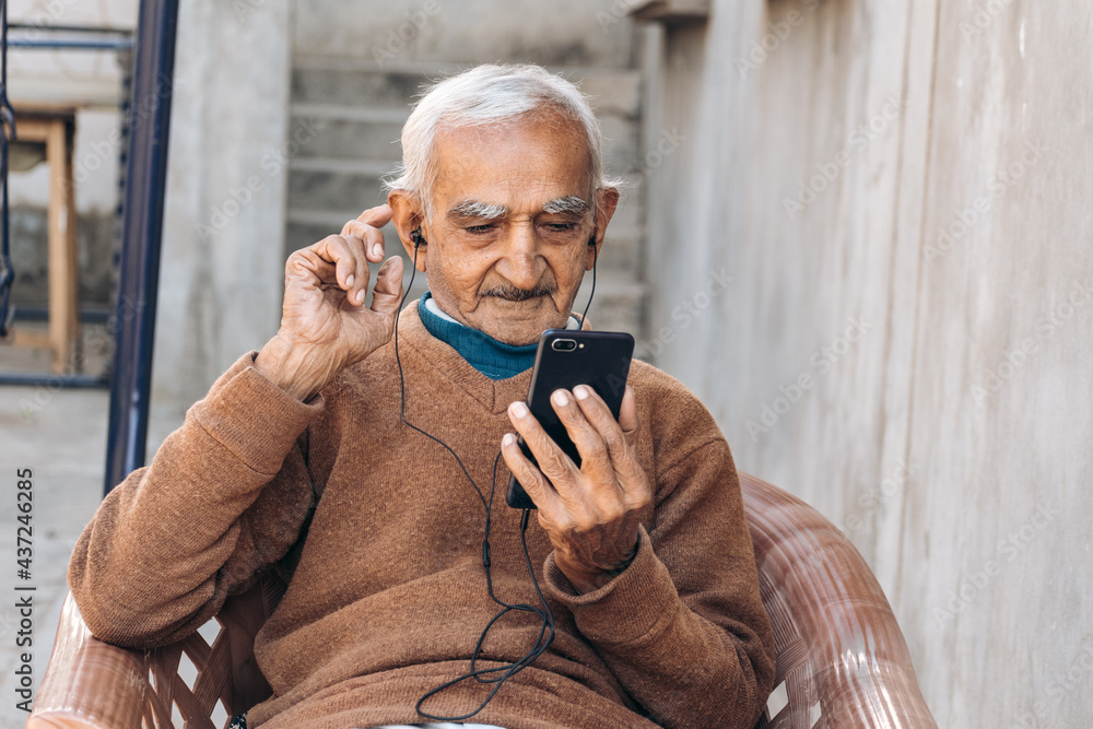 Portrait of happy old Indian man talking on videocall with family with ...