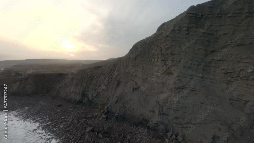 Aerial shot flying over two rally cars riding on pebble waving sea ...