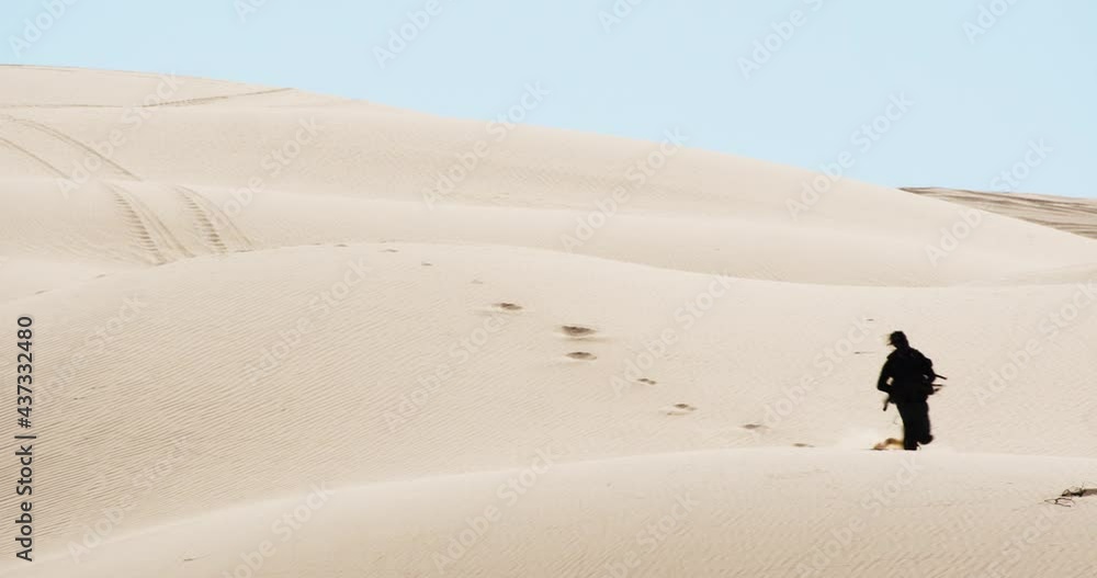 Silhouetted soldier wandering and running alone over sand dunes in ...