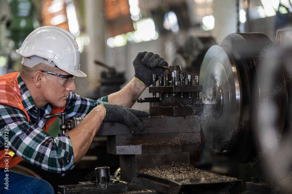 worker is working on a lathe machine in a factory. Turner worker ...
