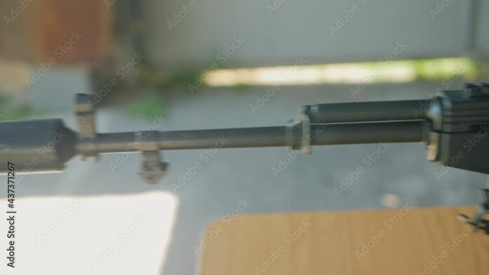 A young man shows off a sniper rifle on various parts. The barrel, the ...