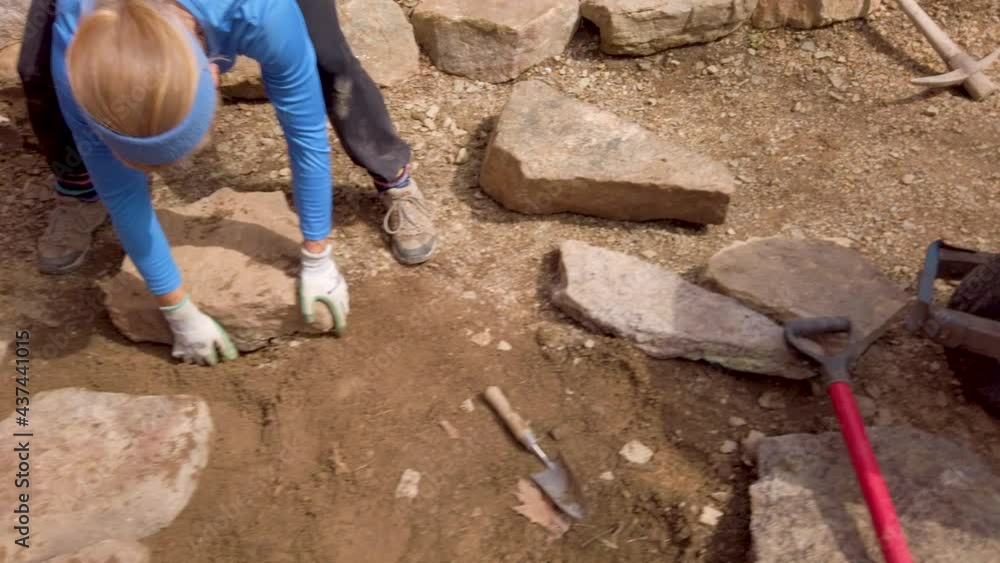 Woman moving large rock pavers for a hardscaping patio project. Stock ...