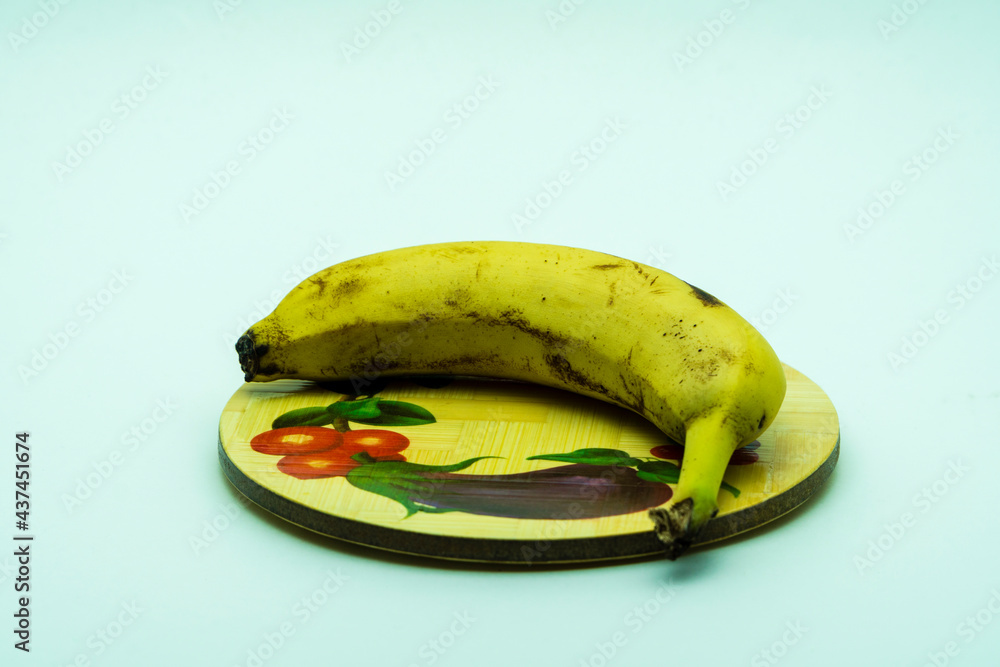 Ugly banana with brown spots lie on round rustic wood plate. Natural ...