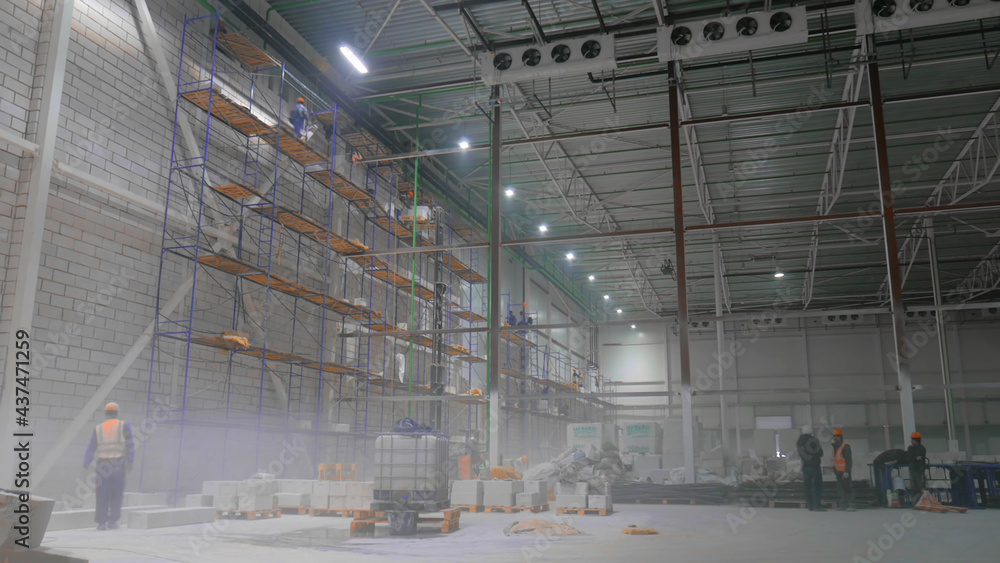 Builders on scaffolding inside large and modern warehouse under ...