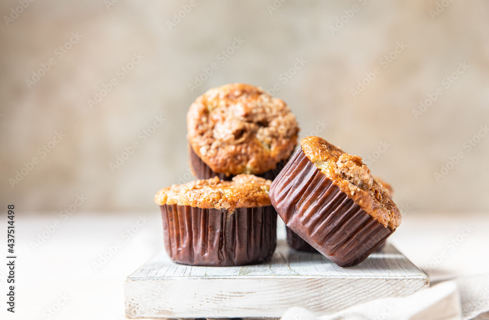 Tasty breakfast muffins with oat crumbs topping on white cutting board ...