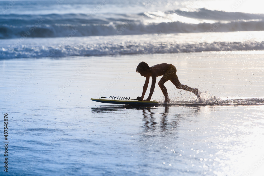 Happy boy - young surfer with bodyboard have fun on beach, run by sea ...