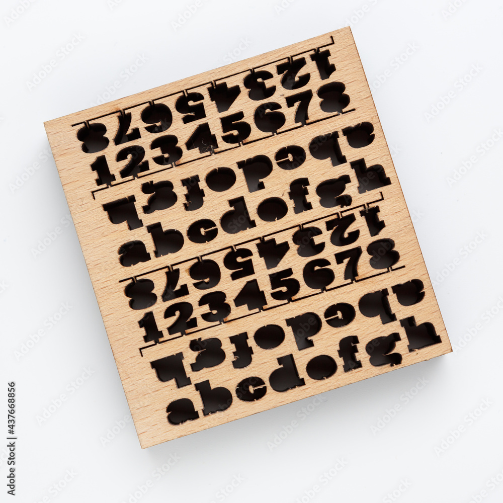 plywood with laser-cut letters and numbers on it. on a white background ...