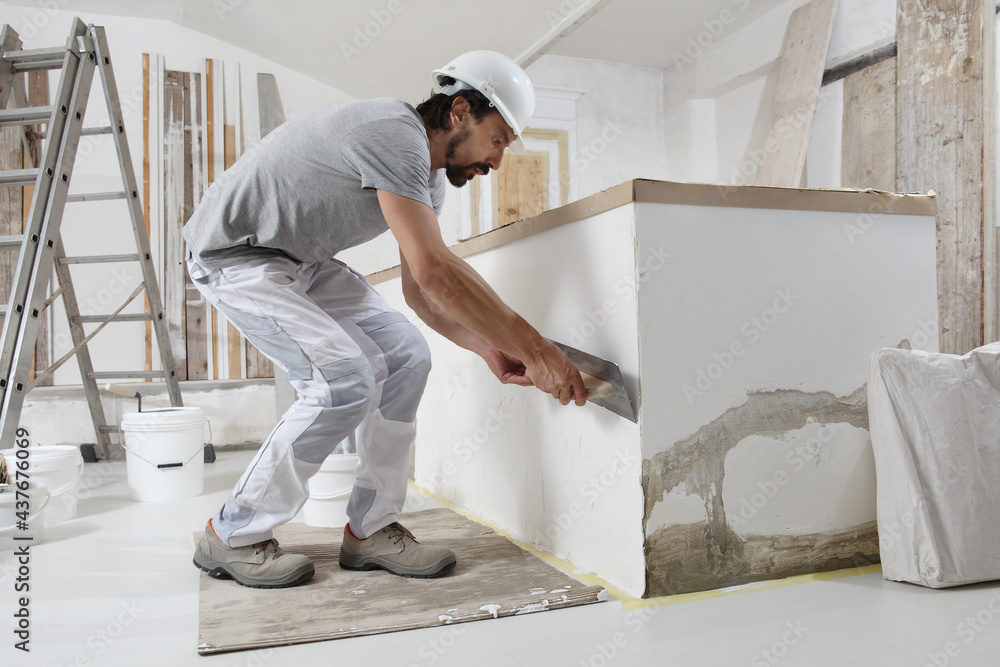man plasterer construction worker at work, takes plaster from bucket ...