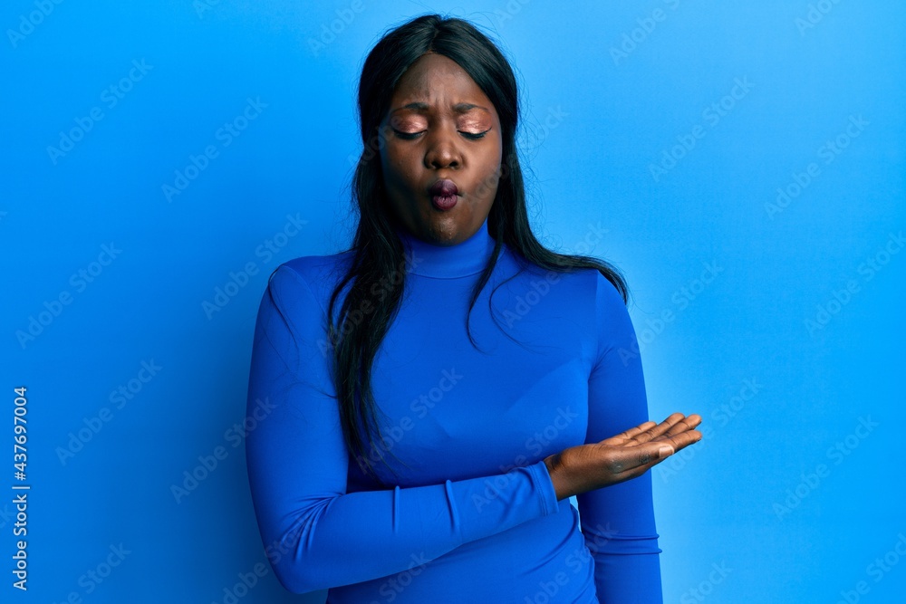 African young woman presenting with open palm to the side making fish ...