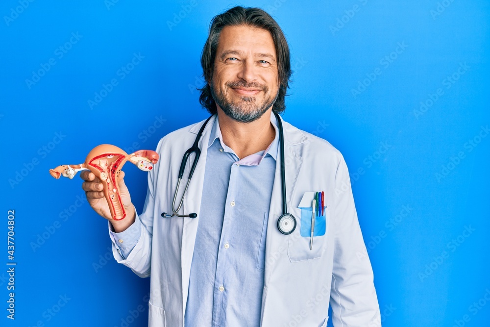 Middle age handsome gynecologist man holding anatomical model of female ...
